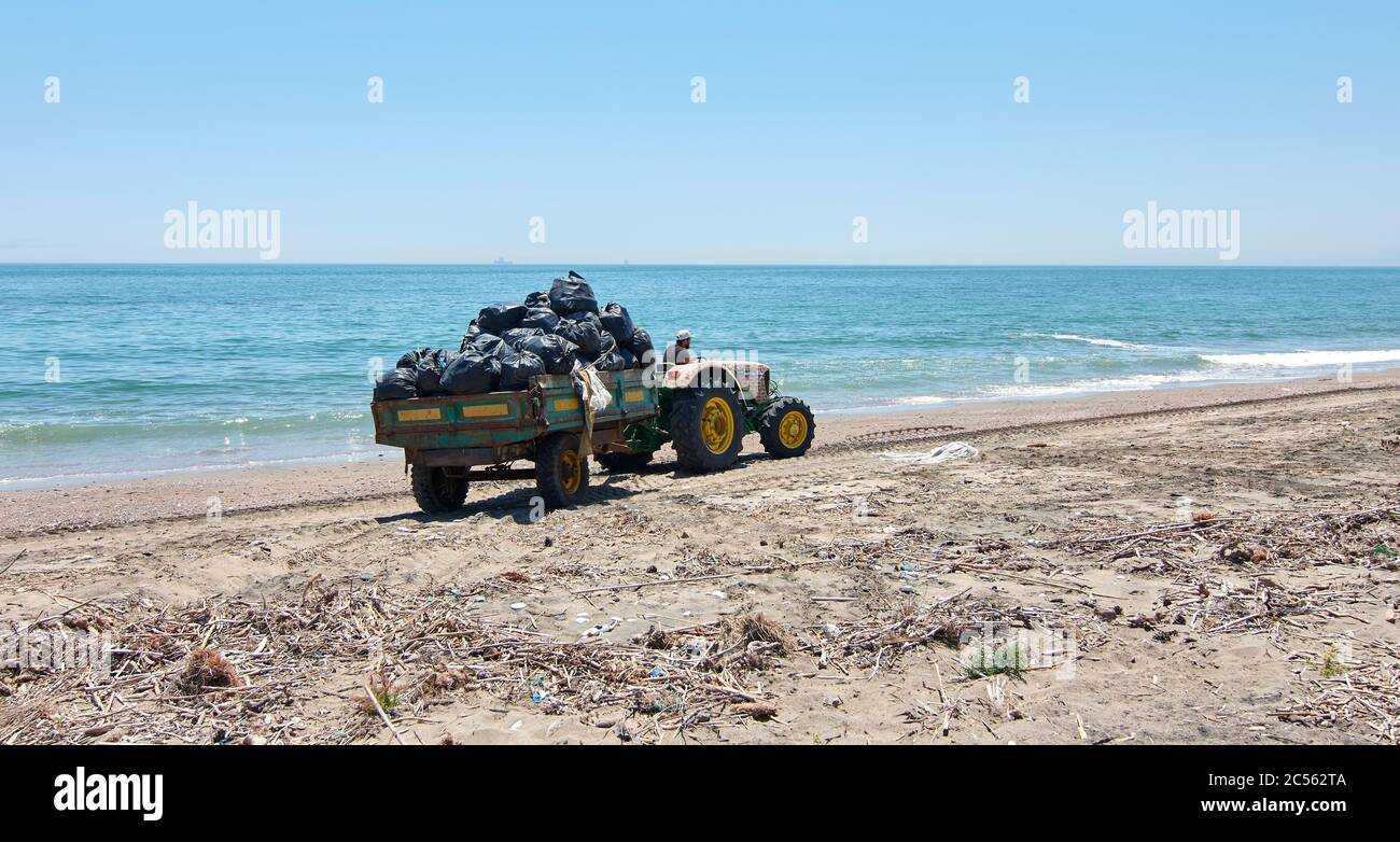 Man driving a tractor while collecting garbage on a seashore Stock ...