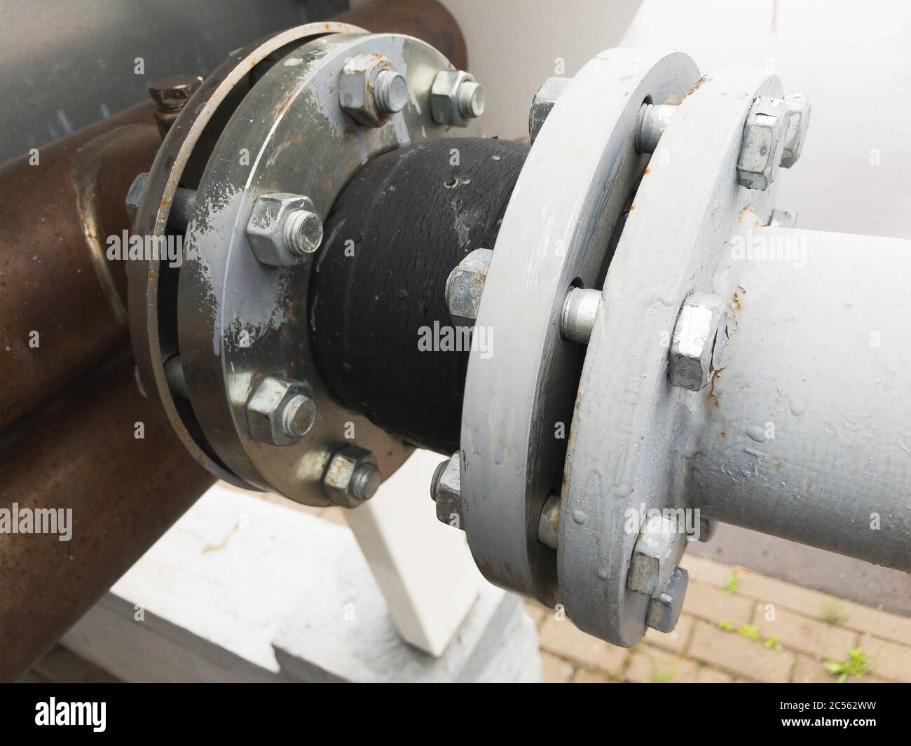 Old grey painted rubber expansion joint with cracks in the pipeline in ...