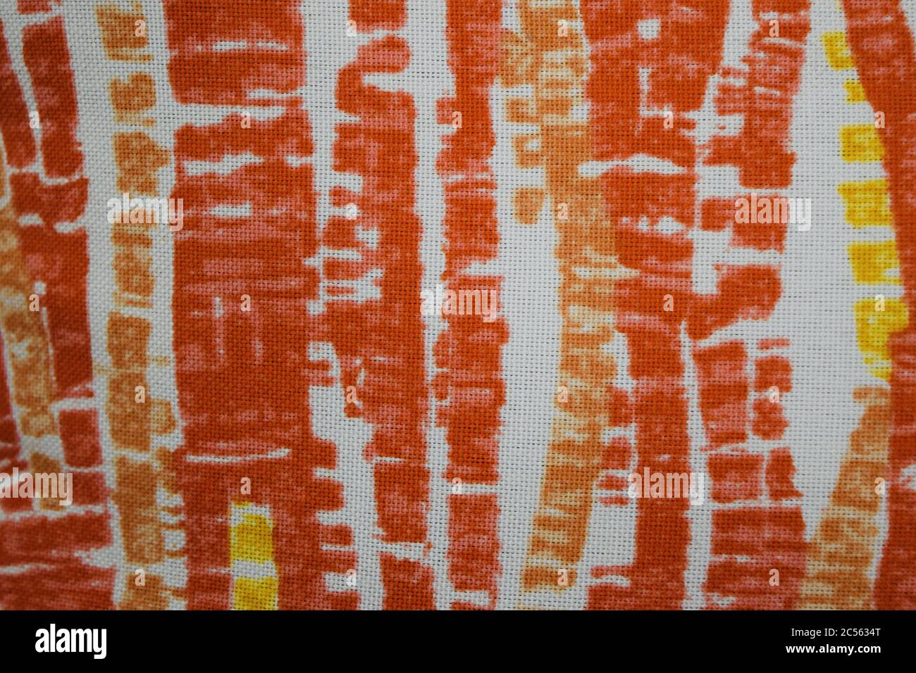 Bright colorful fabric with orange and yellow broken wavy lines on a ...