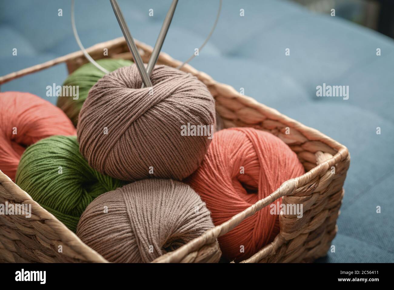 Colored yarn balls in rustic wicker basket on blue couch closeup Stock ...