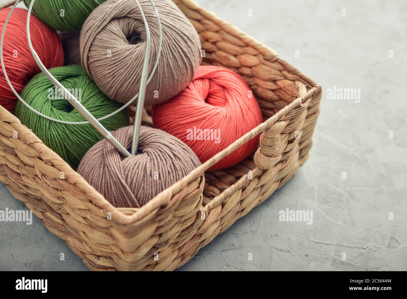 Colored yarn balls in wicker basket on grey background closeup Stock ...