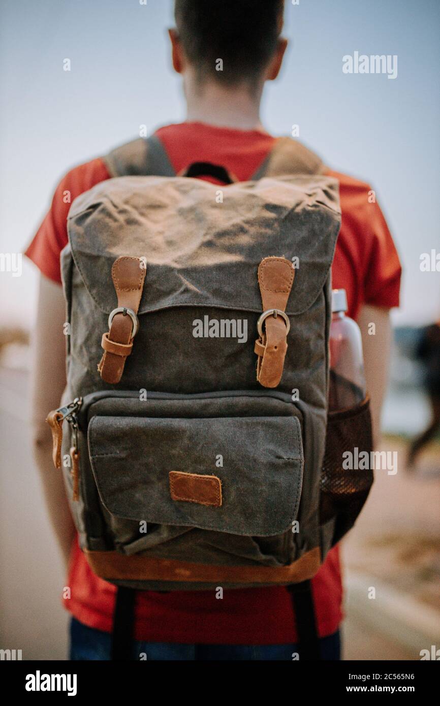 Vertical shot of a male wearing a grey leather backpack with brown ...