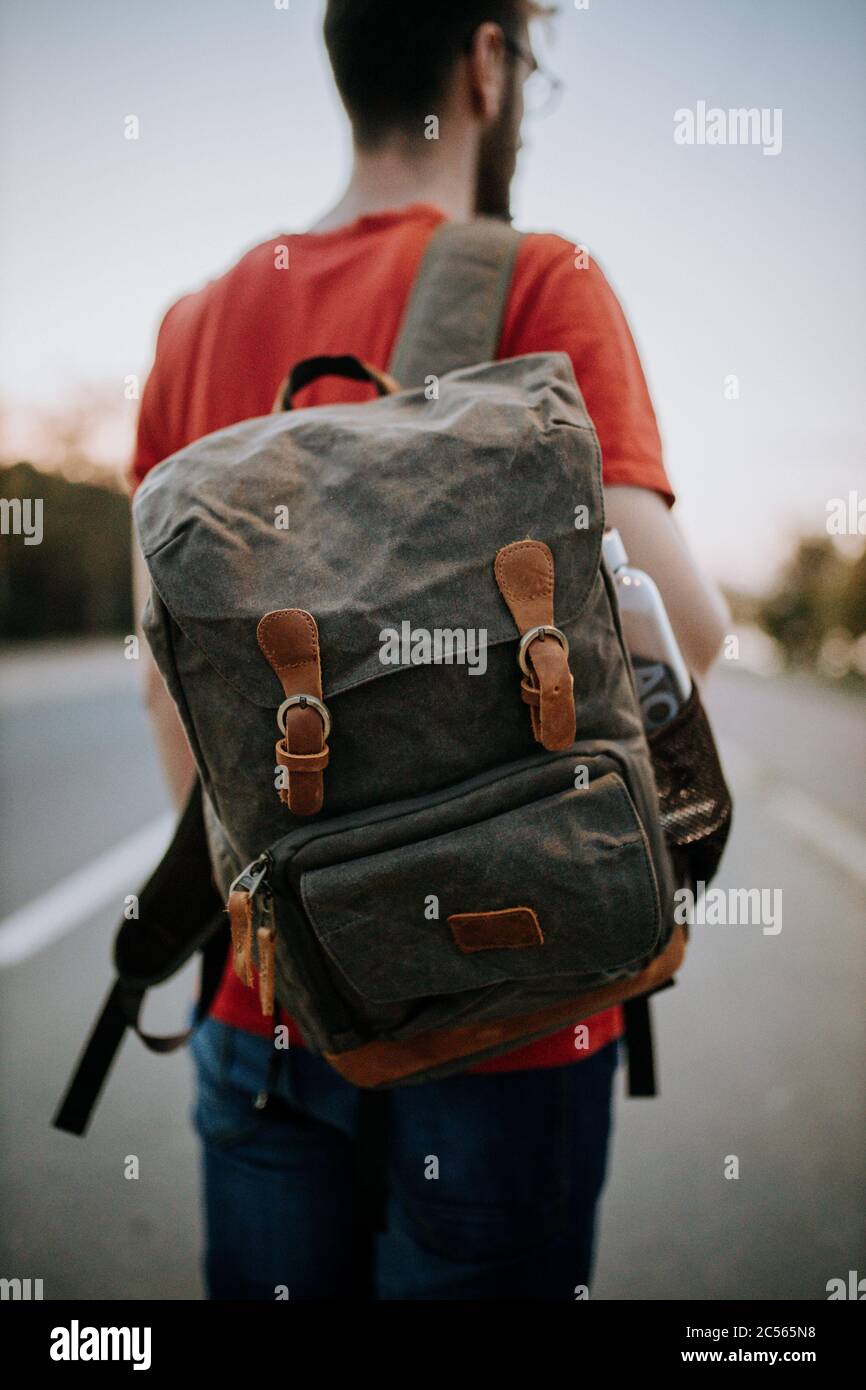 Vertical shot of a male wearing a grey leather backpack with brown ...