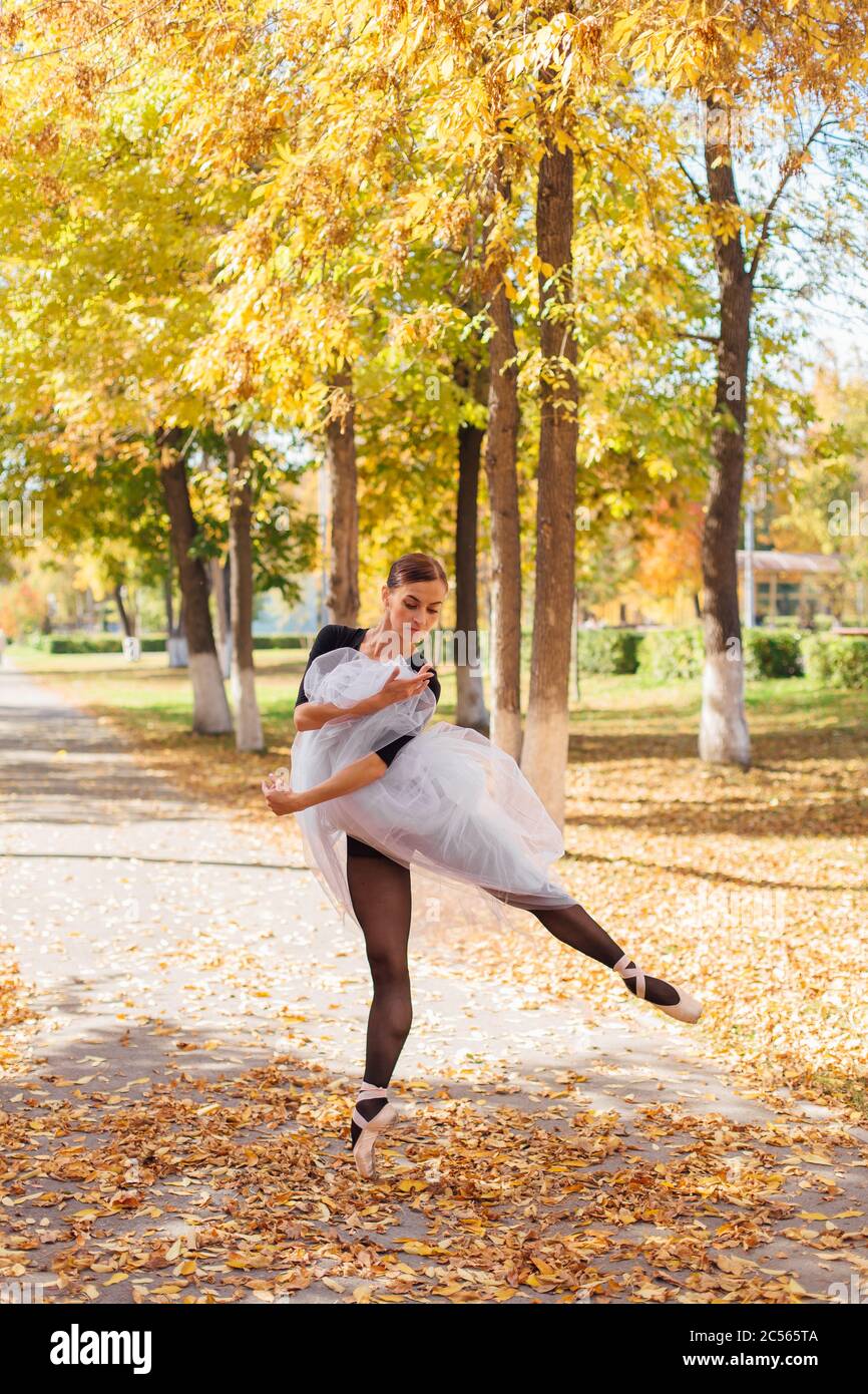 Woman ballerina in a white ballet skirt dancing in pointe shoes in a ...
