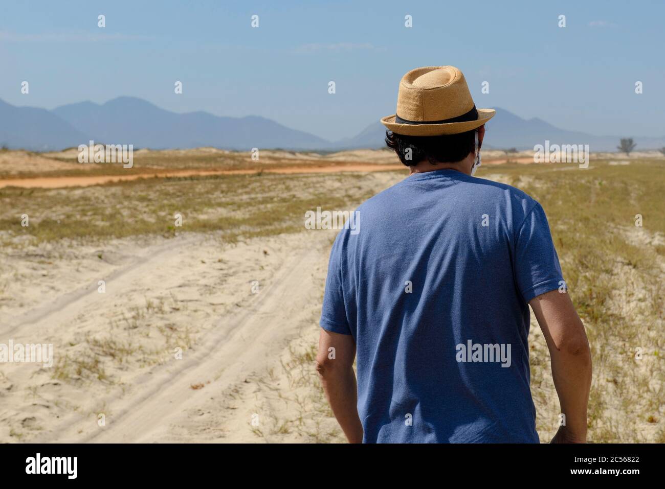 The new normal - man with hat walking through an area near the beach ...