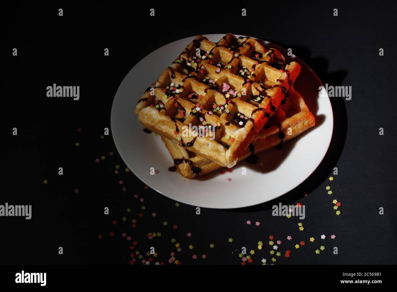 High angle view of Belgian waffles on a plate with syrup and sprinkles ...