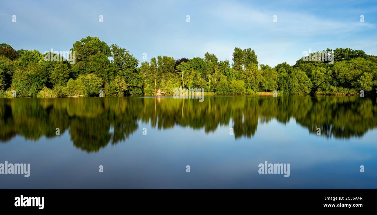 Beautiful scenery of a lake with the reflection od surrounding green ...