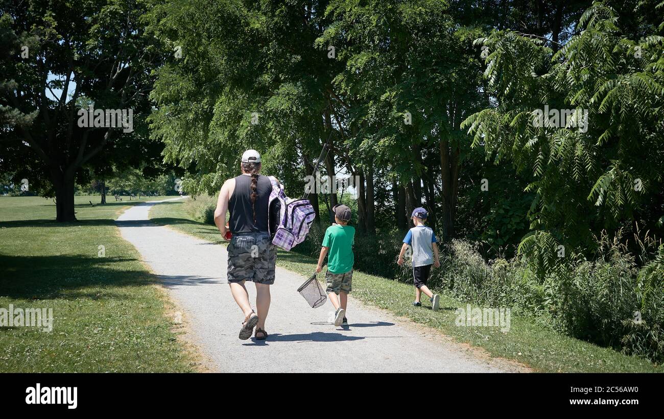 Father with pigtail walks with his two boy as they head to their ...