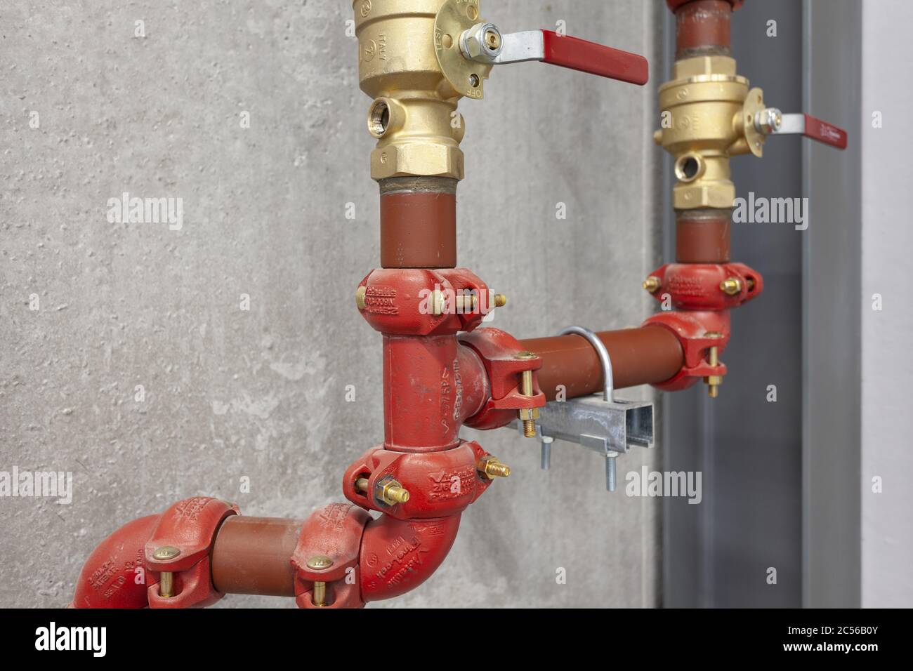 Closeup shot of a red pipe with valves on grey wall background Stock ...