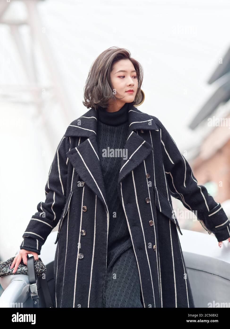 Fashion Chinese woman in black overcoat standing and looking away Stock ...