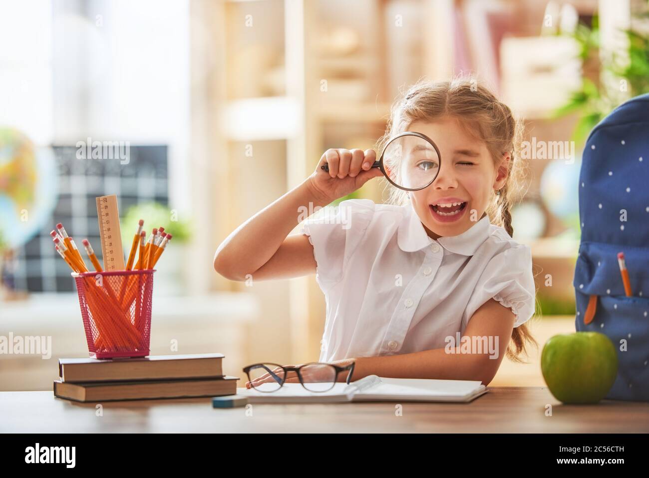 Back to school! Happy cute industrious child is sitting at a desk ...