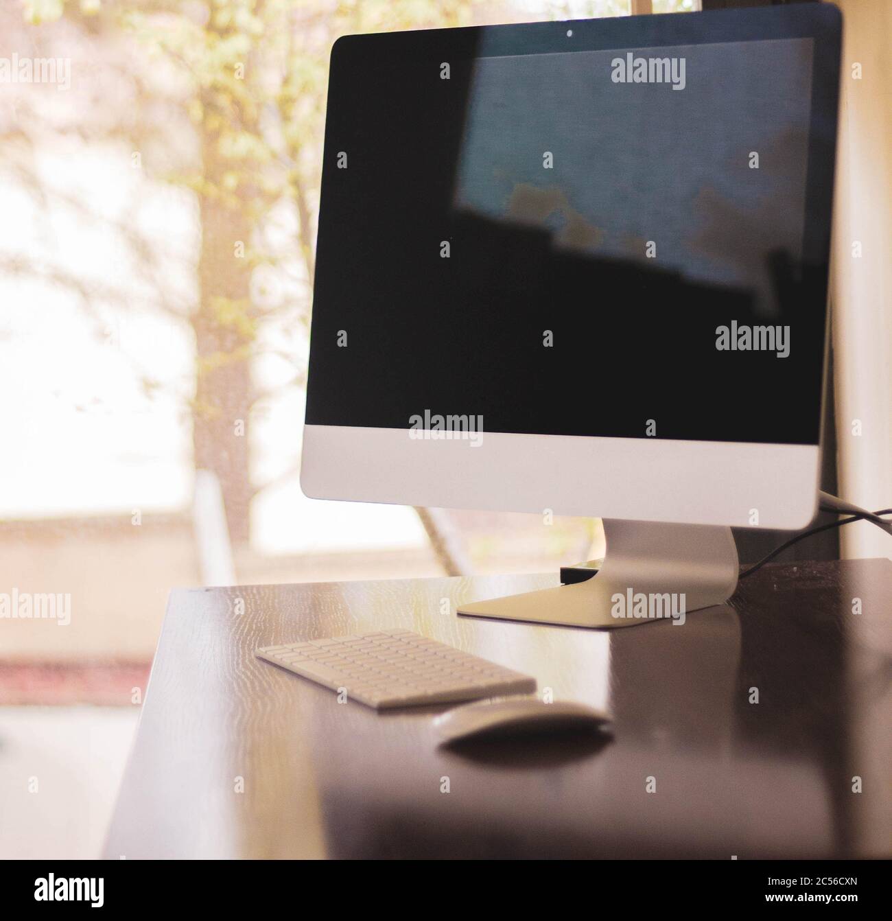 desktop computer on wooden table against light window with trees Stock ...