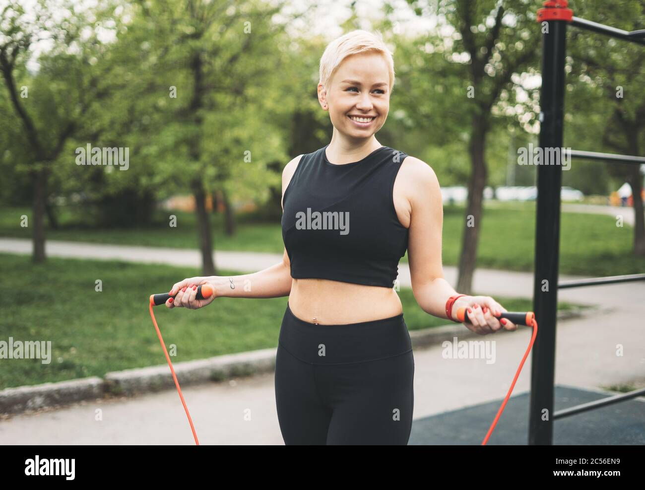 Attractive fit young woman in sport wear training with skipping rope on ...