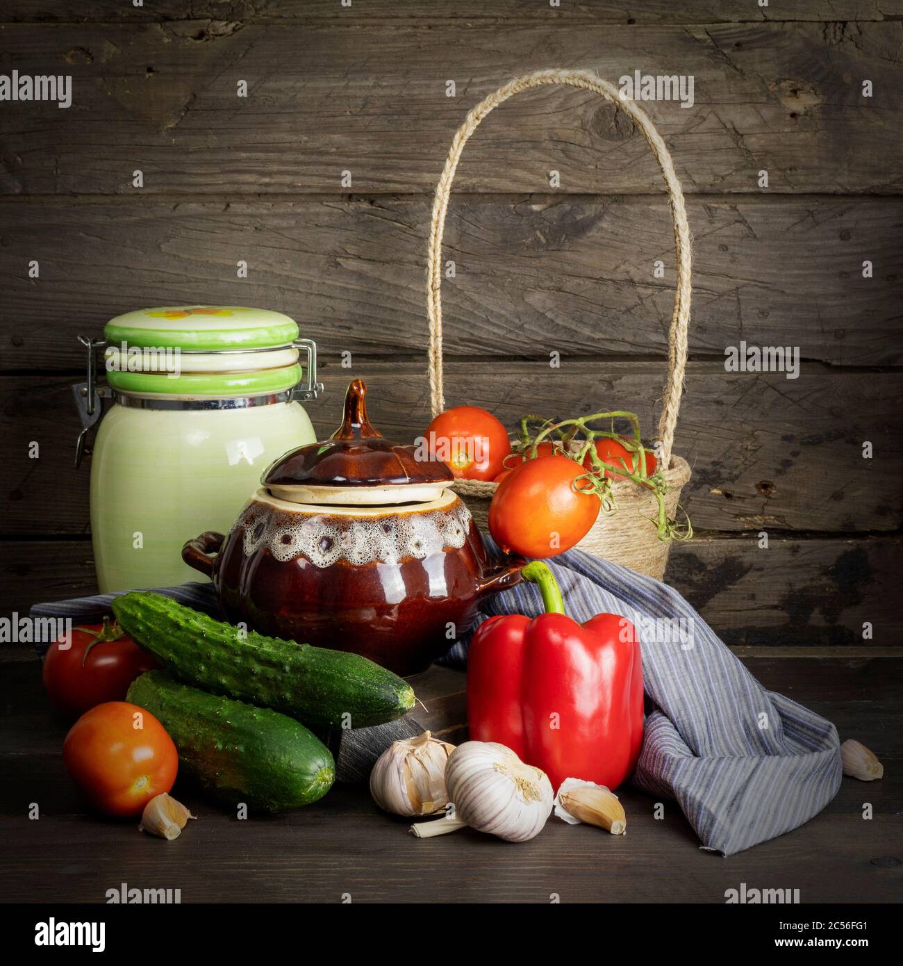 Still life with ceramic pots and fresh vegetables on a wooden ...