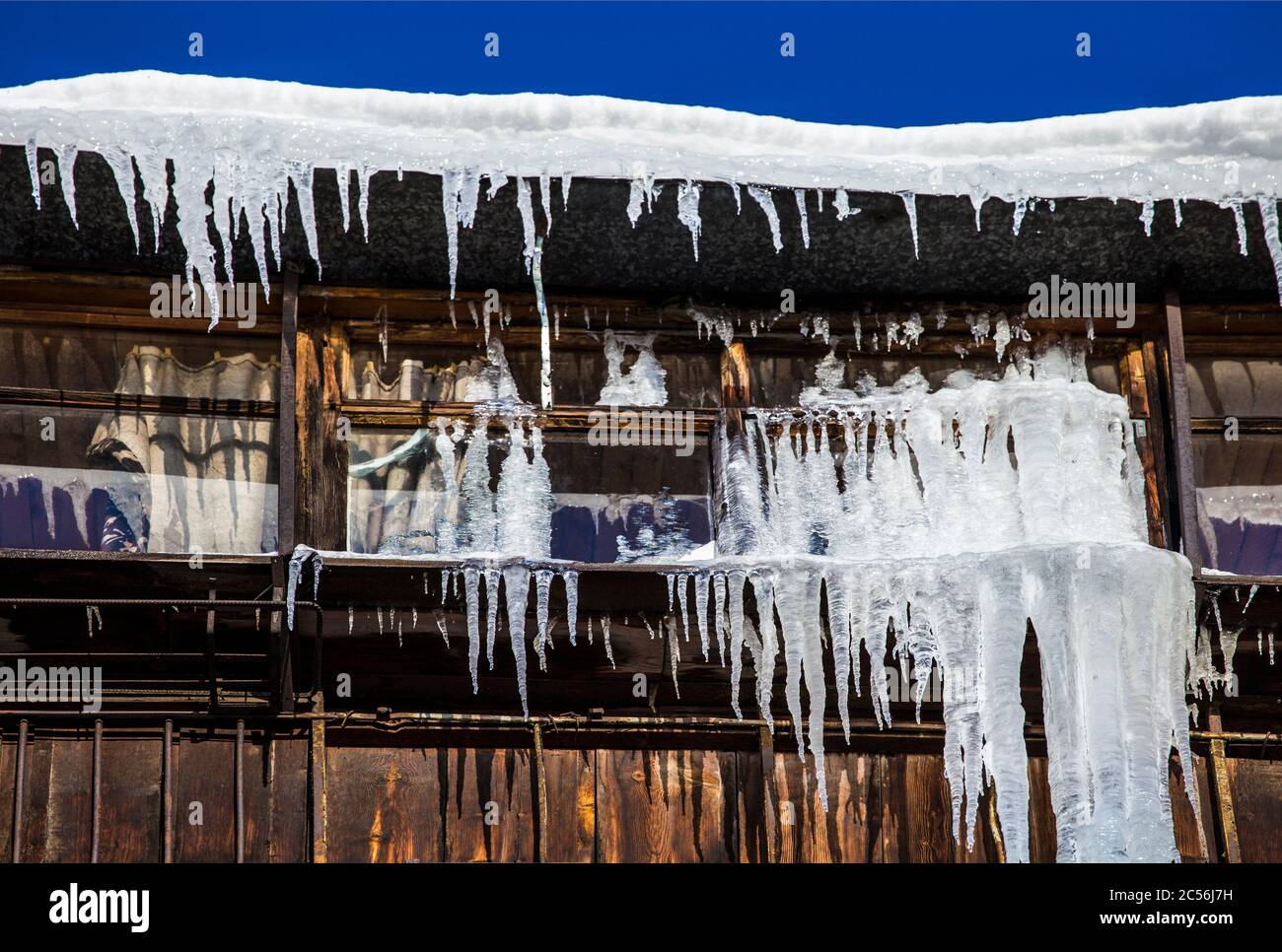 Large icicles hang from a house roof. Dangerous large icicles Stock ...