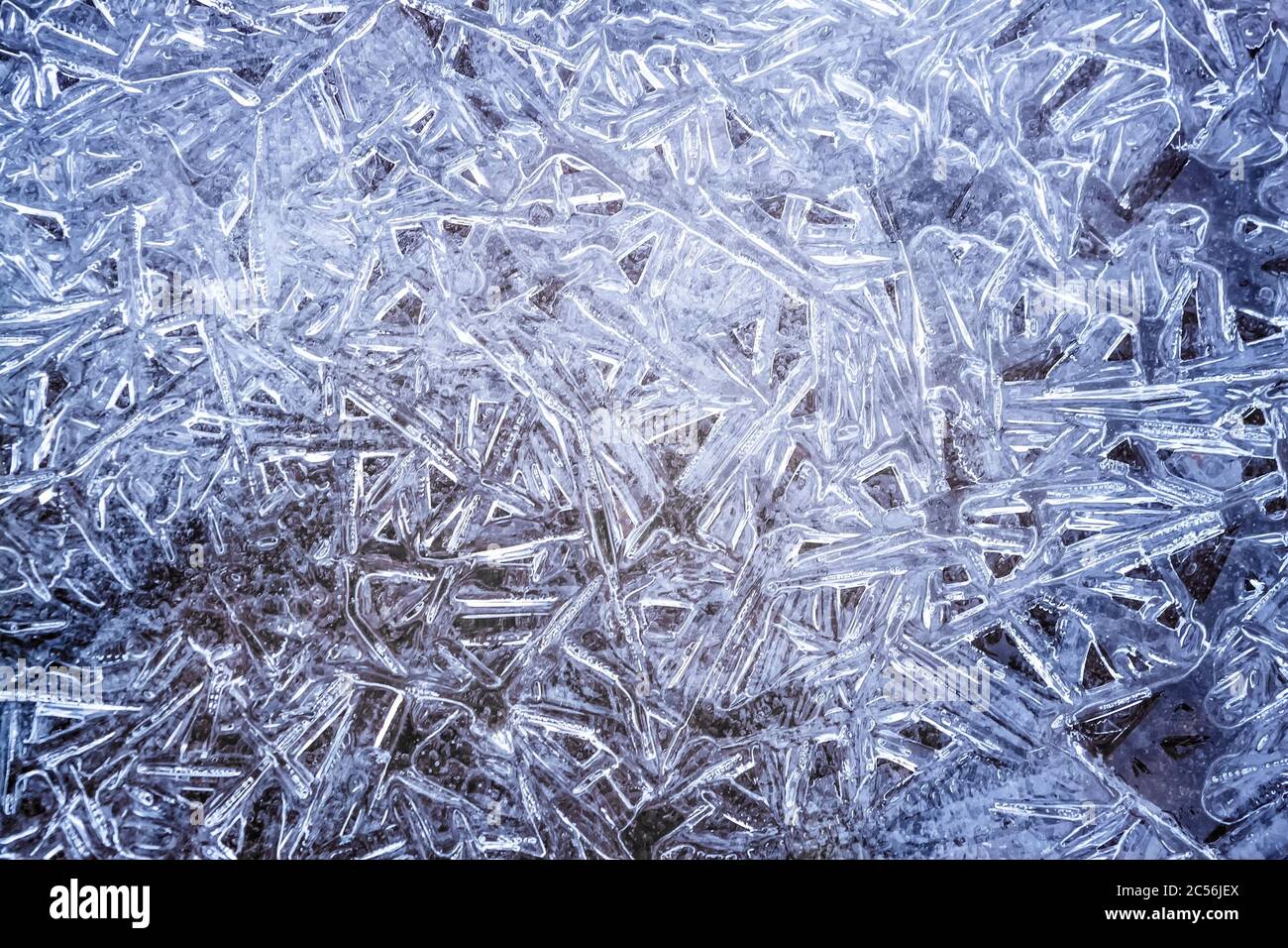 Beautiful frost ice crystals on frozen puddle water, blue color ...