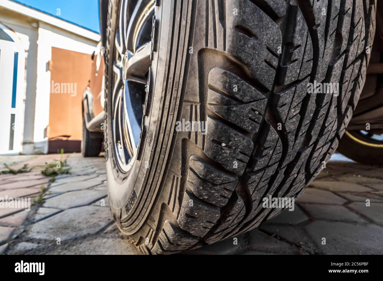 Tread of a wheel of an off-road car standing in the back yard, closeup ...