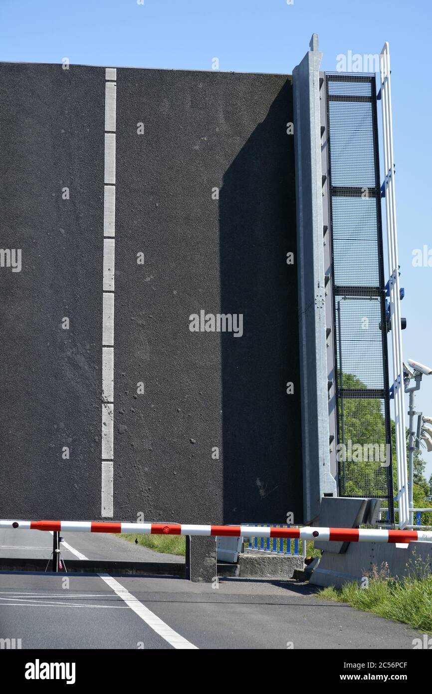 Striped schlagbaum in front of an opening bridge with white paint lines ...