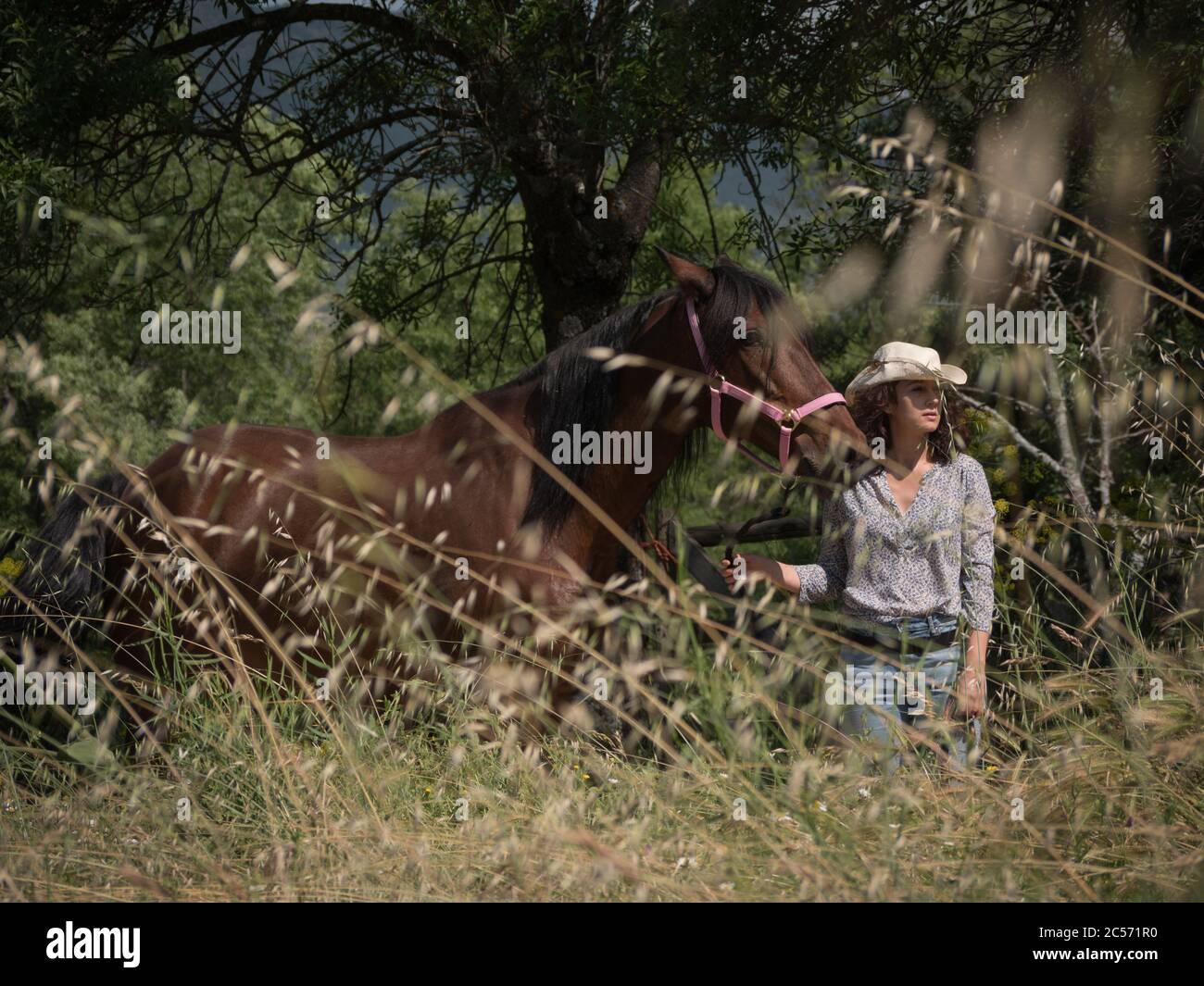 Portrait of female rider wearing a western hat and her andalusian mare ...