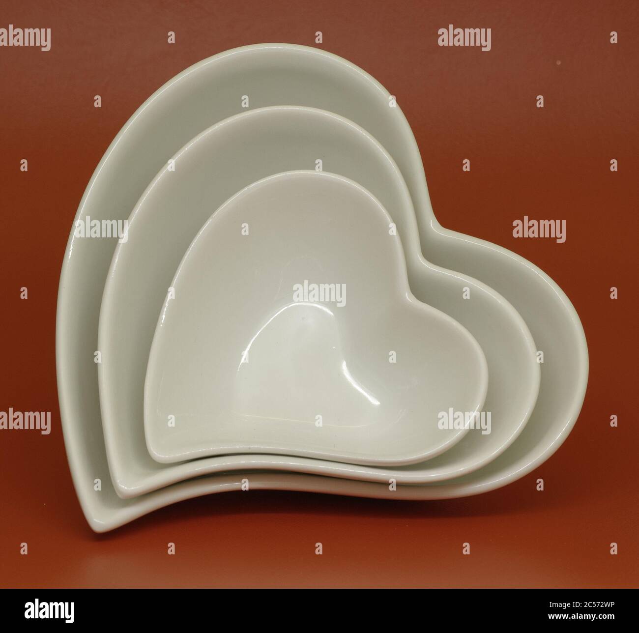 Overhead shot of different sized heart-shaped plates on a red ...