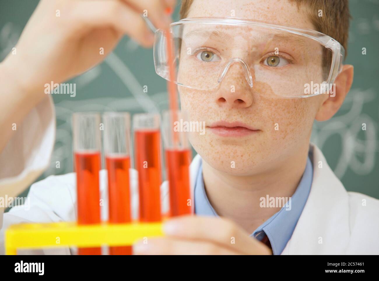 Curious junior high school boy examining liquid in science test tubes ...