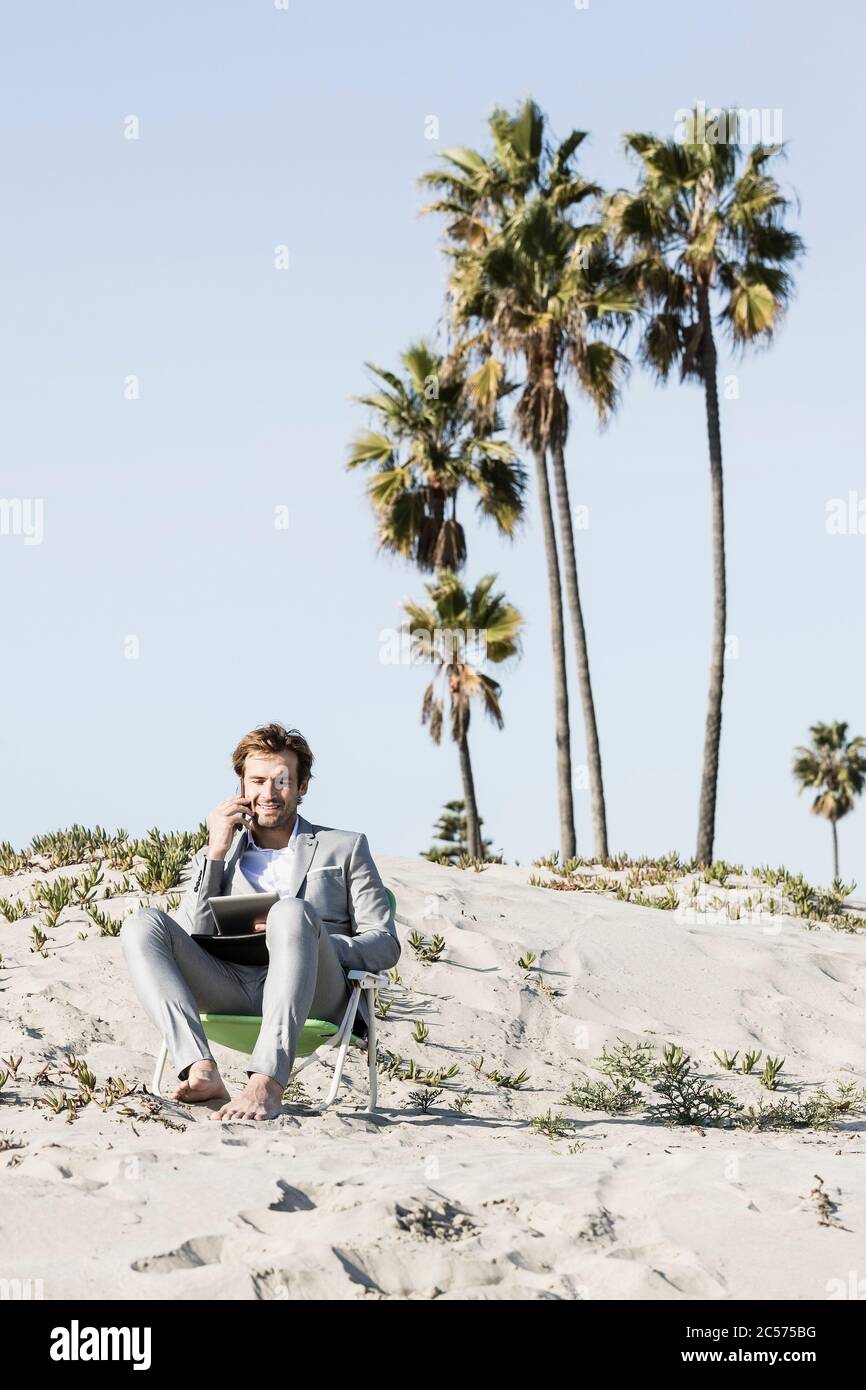 Barefoot businessman with digital tablet and smart phone working on ...