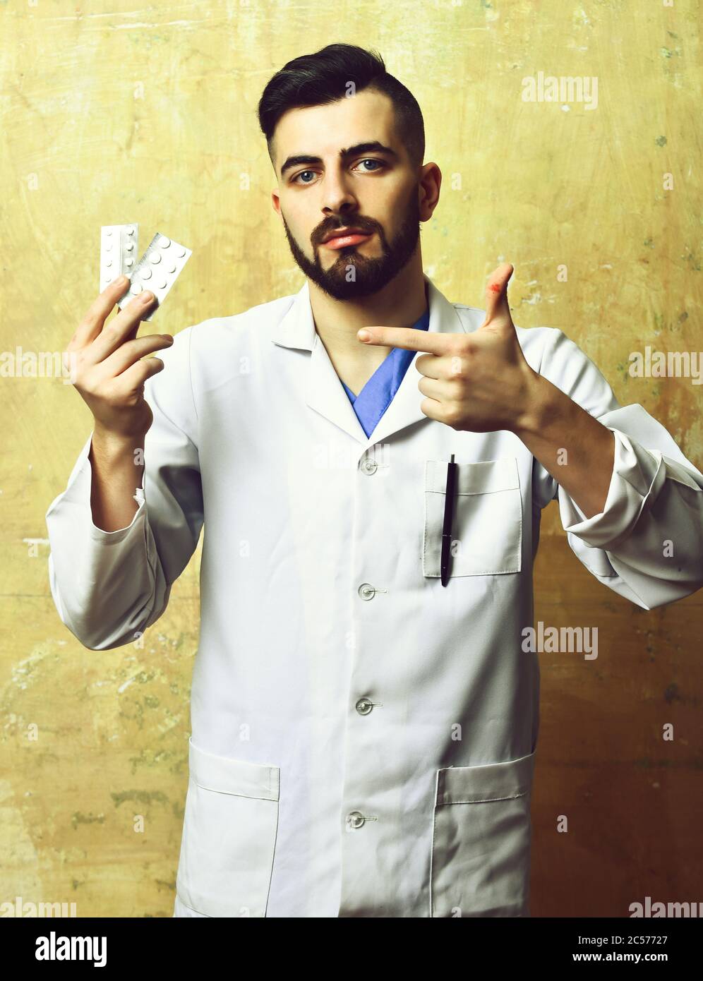 Doctor with beard, stylish haircut and assured face expression pointing ...