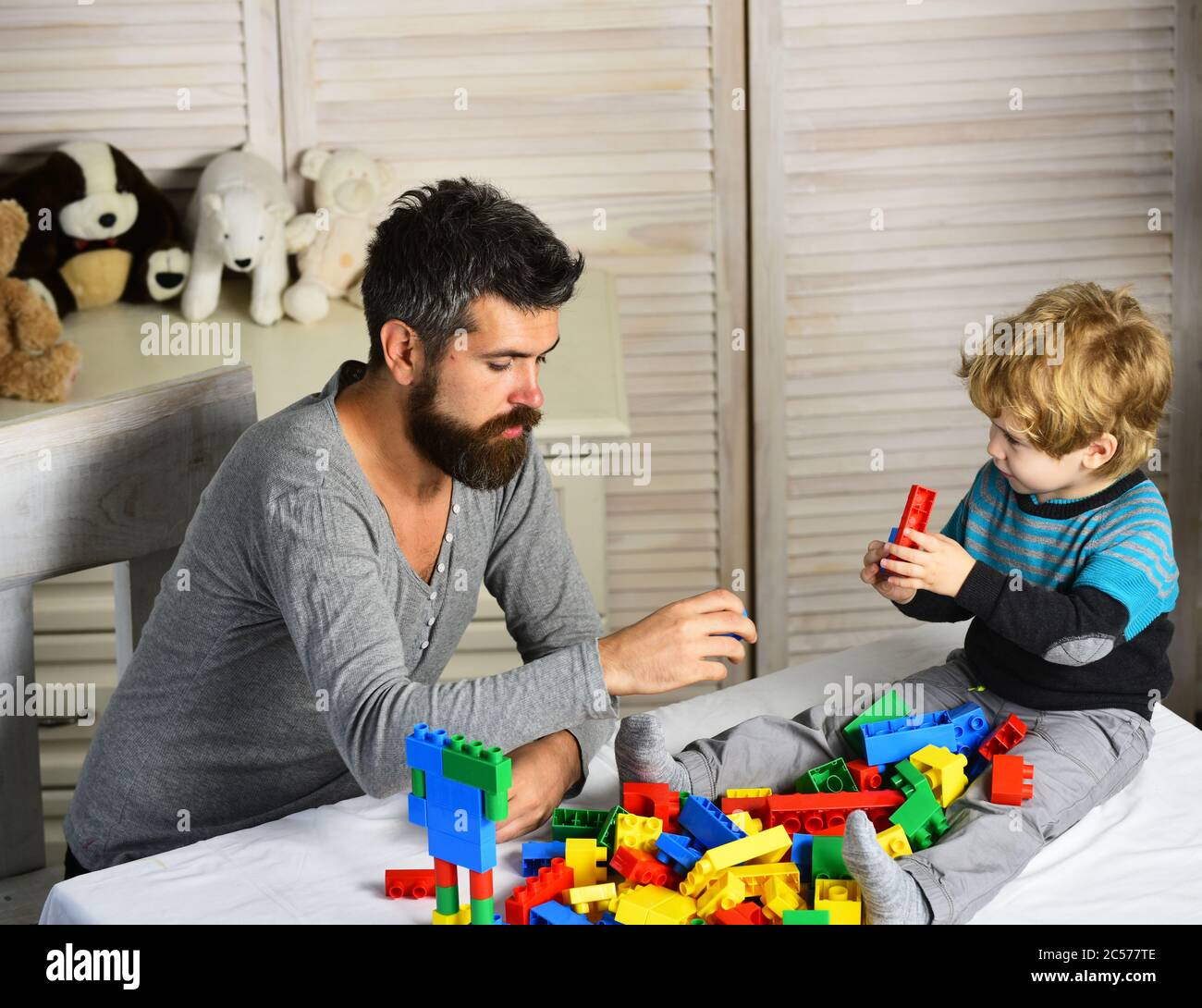 Dad and kid with toys on background build of plastic blocks. Father and ...