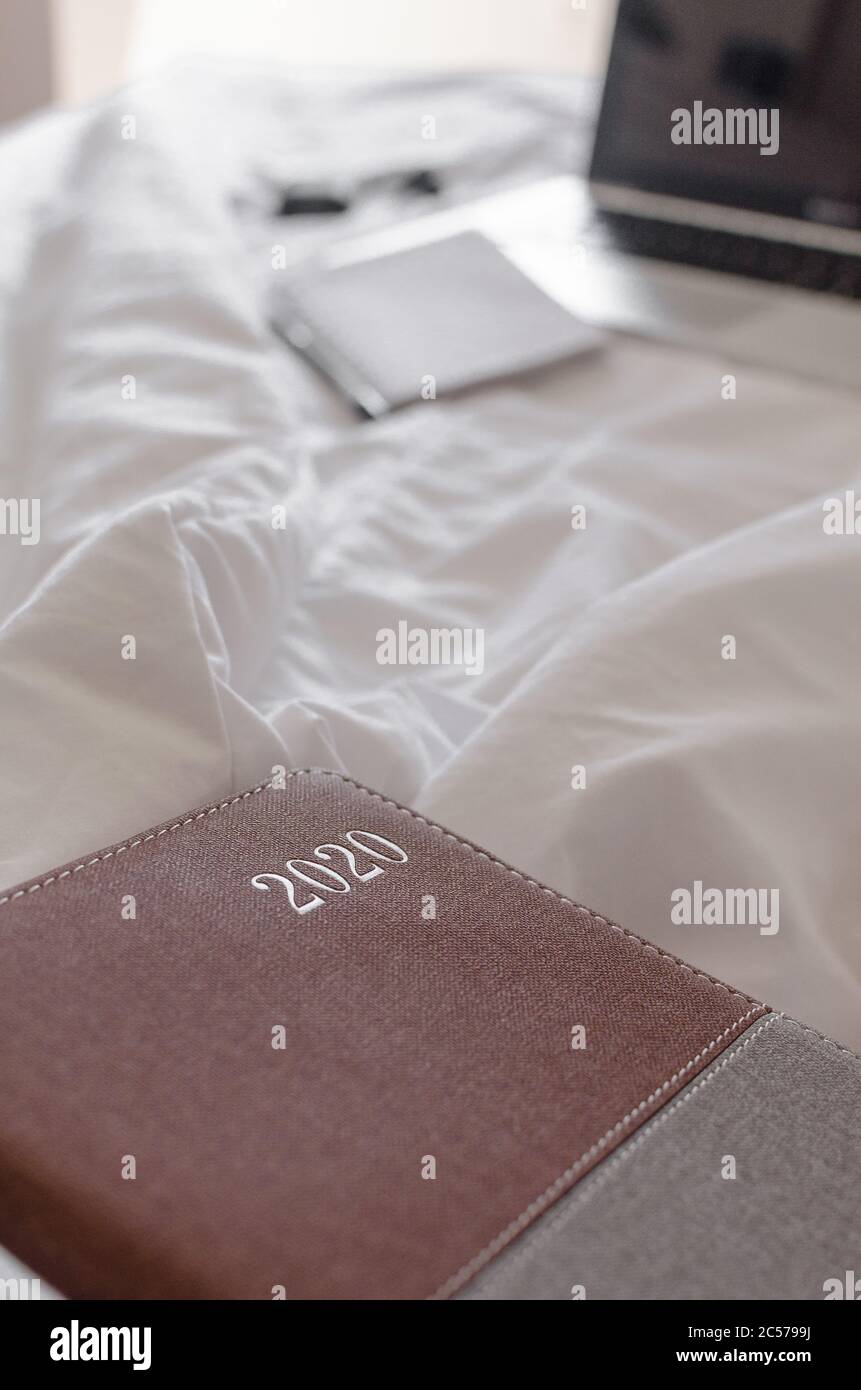 2020 calendar notebook along with a laptop, black wireless earbuds and ...