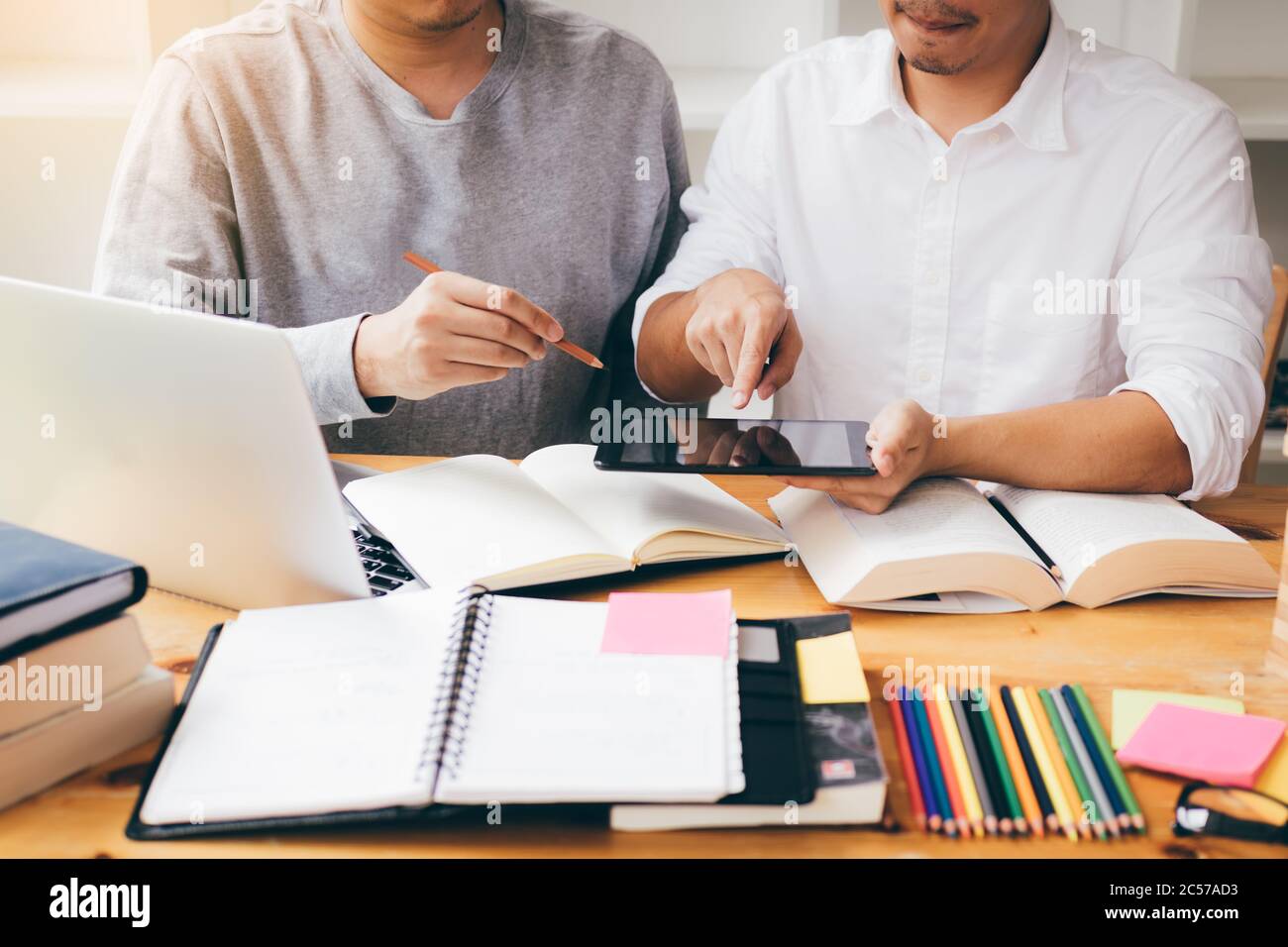 Two students studying and learning in library with a laptop and notes ...