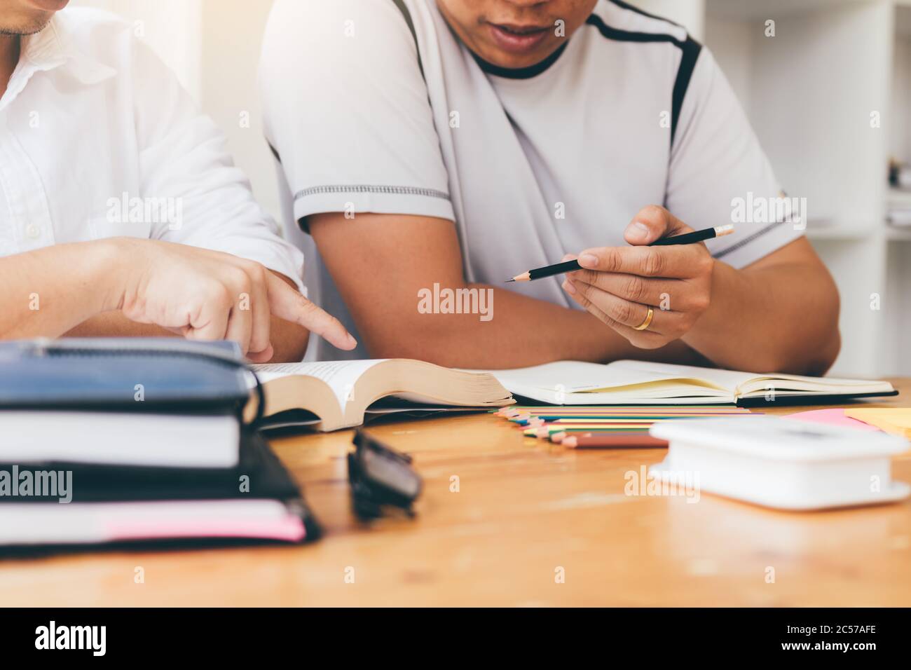 Student reading textbook for test together in library Stock Photo - Alamy