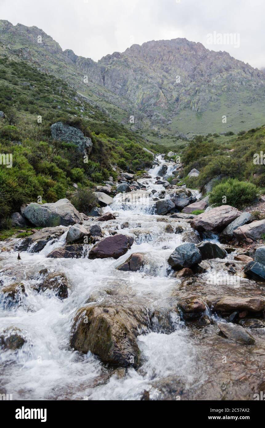 Vertical shot of a flowing river in Andes mountain, Argentina with a ...