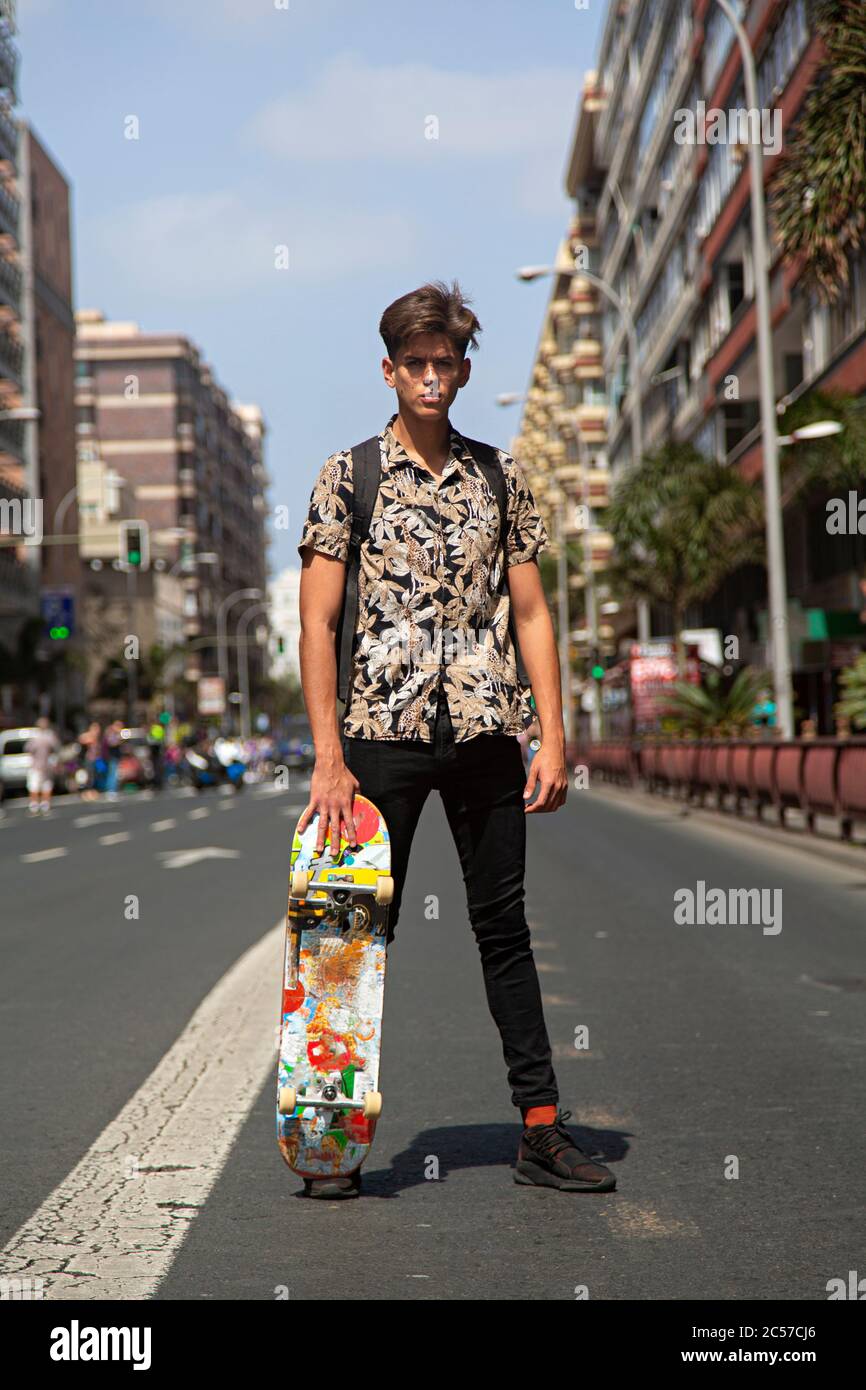 Portrait of young skateboarder man with bad boy face in the middle of ...