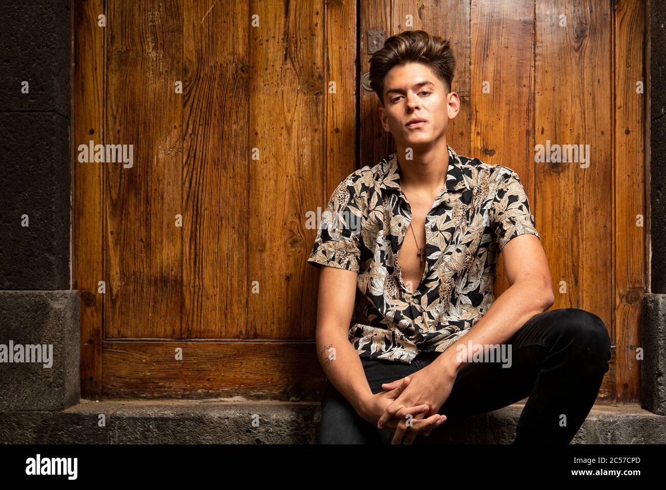 Portrait of young model with tough guy look with wooden door background ...