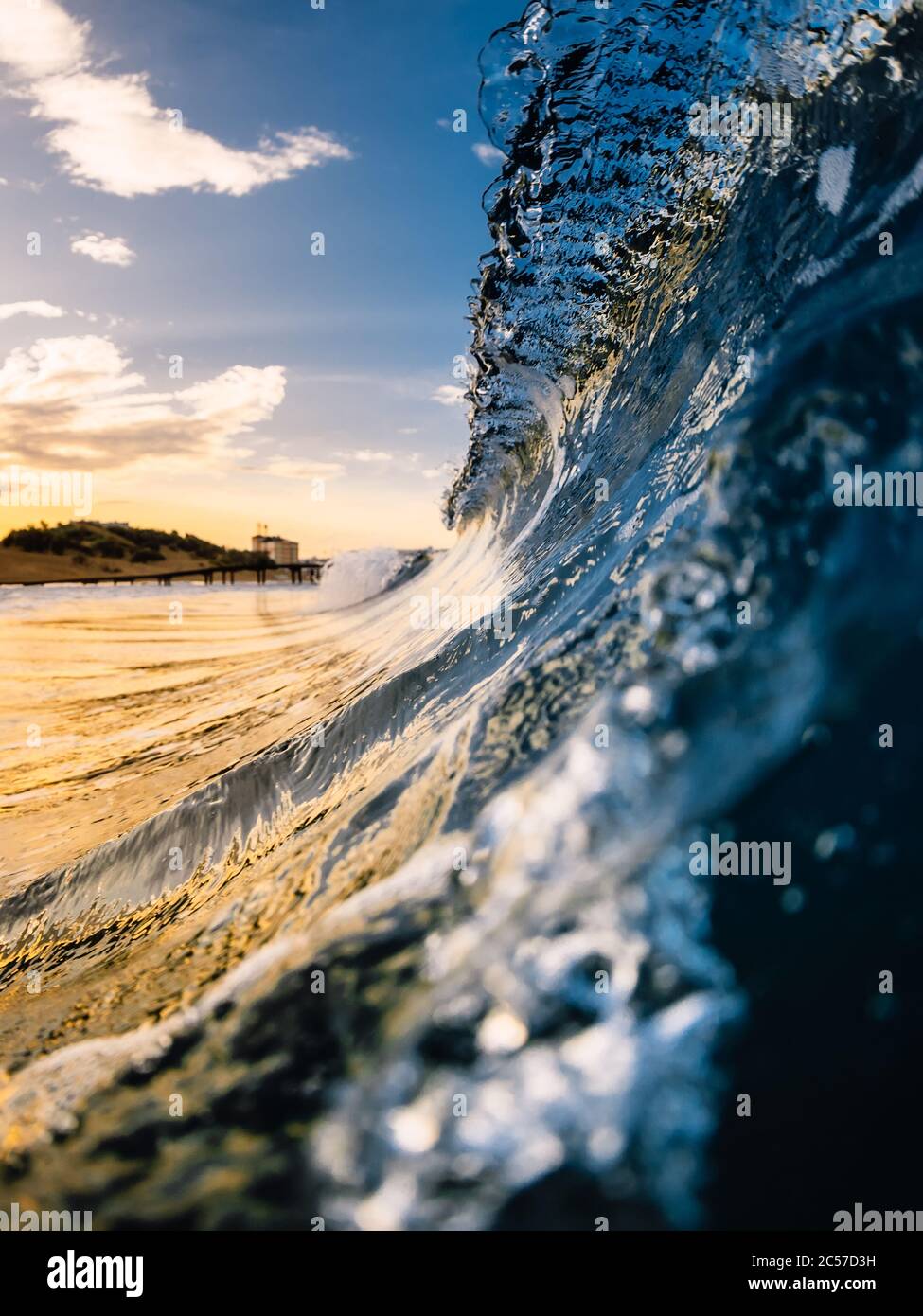 Barrel crashing wave in ocean with warm tones and beach Stock Photo - Alamy