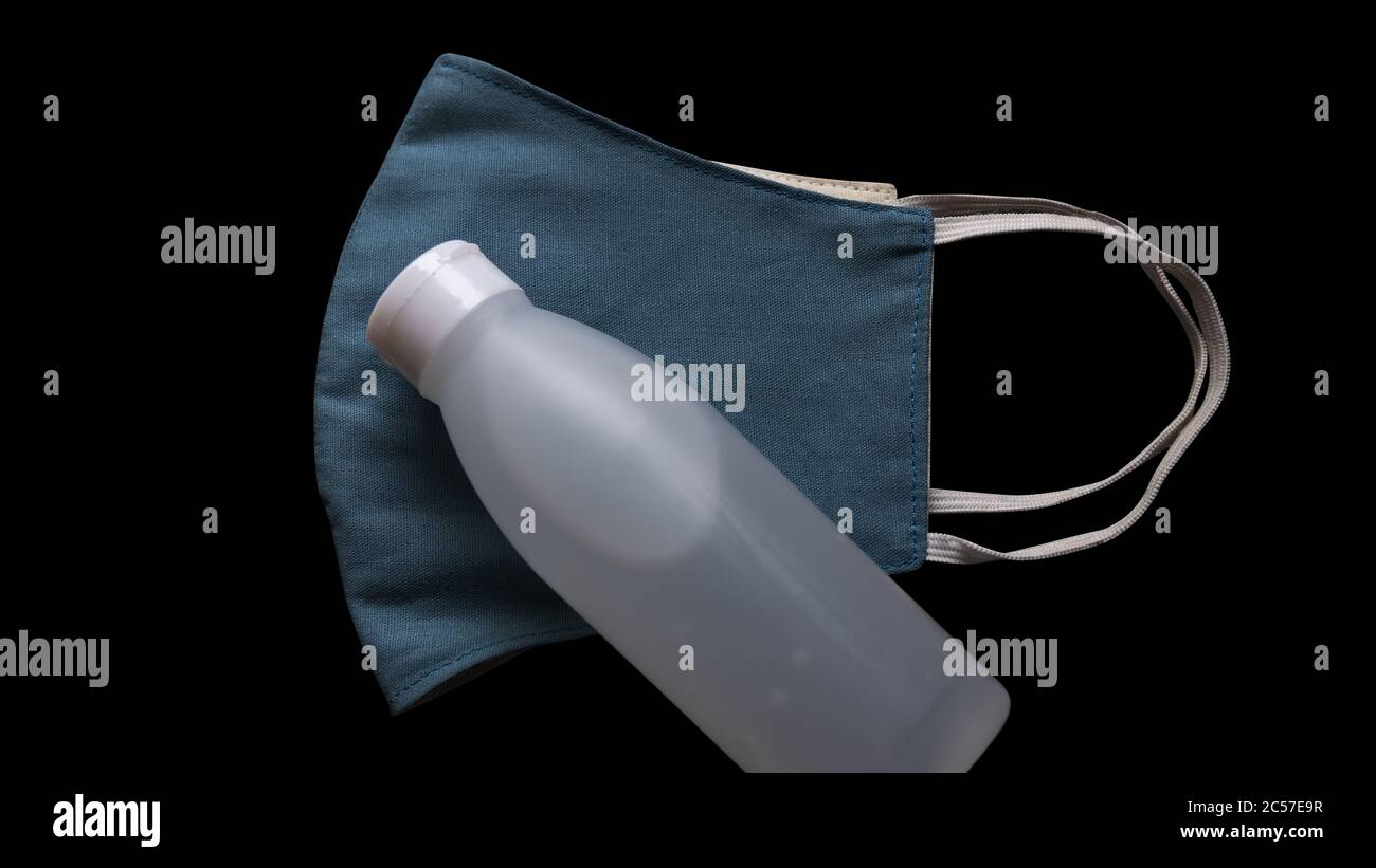 Overhead shot of a blue face mask and a bottle of rubbing alcohol on a ...