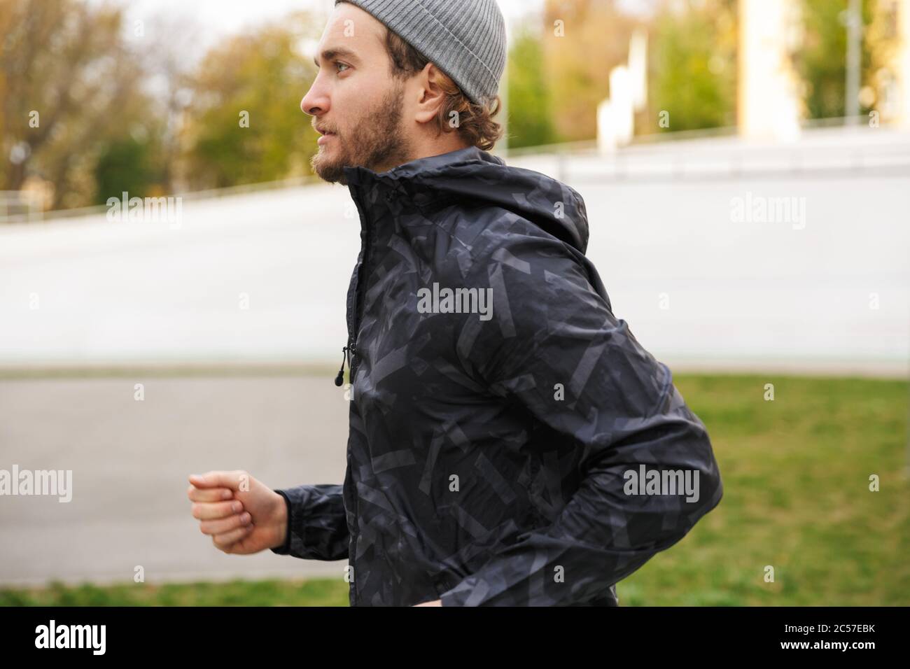 Side view of a confident young fit sportsman running on the race track ...
