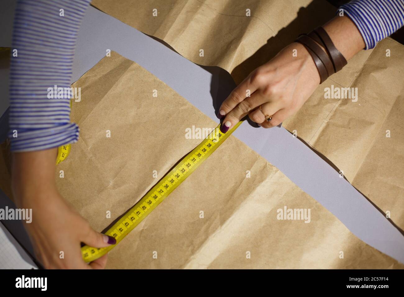 Close-up of a seamstress's hand with a centimeter. Measures the cut ...