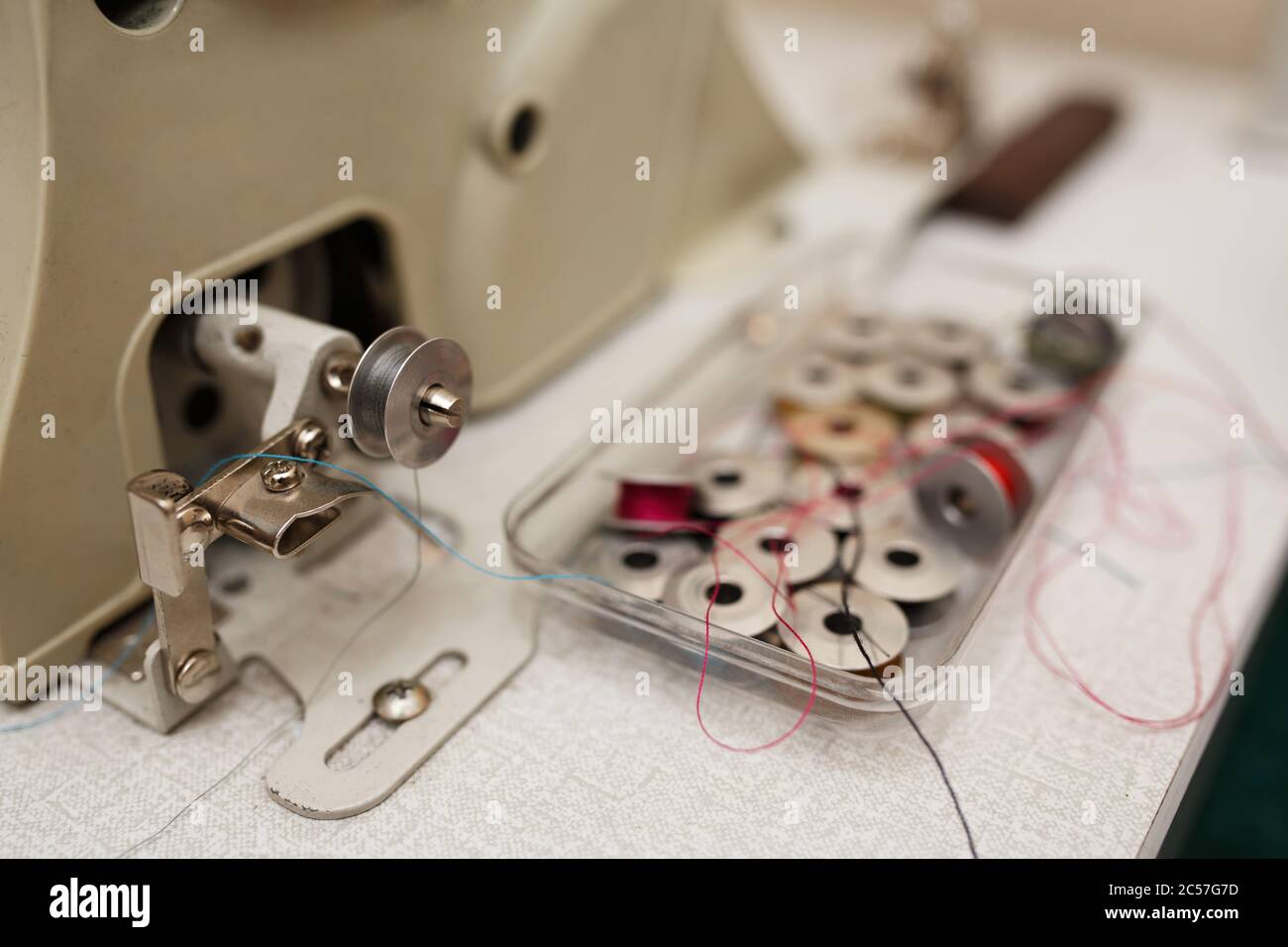 box with metal spools of colored threads near sewing machine. And one ...