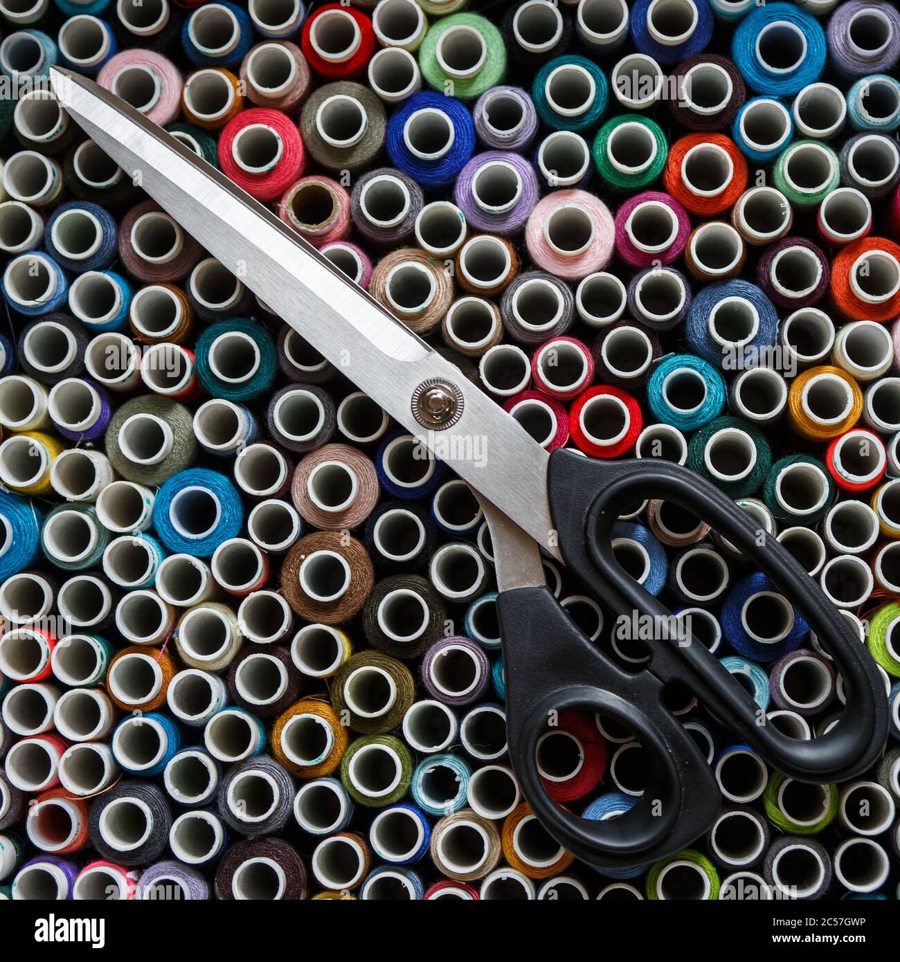Top view of the box with colored threads on which are large scissors ...