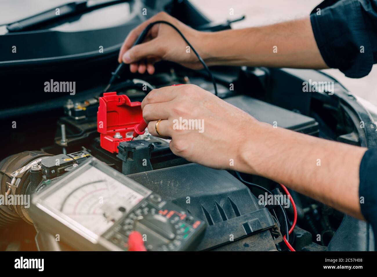 Car mechanic is using the car battery meter to measure various values ...