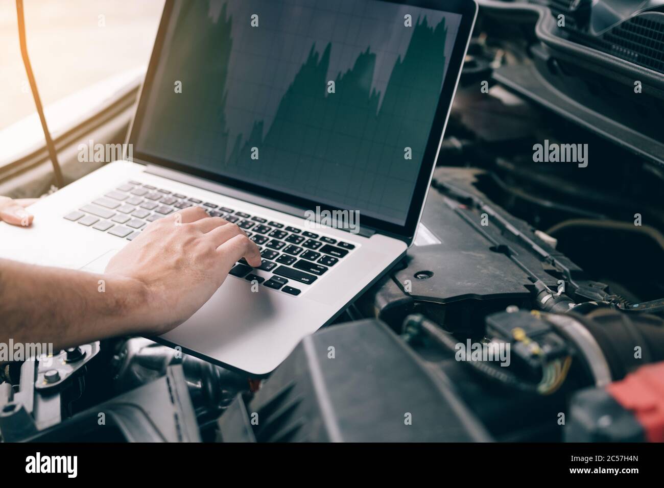 Car repair technicians use laptop computers to measure engine values ...