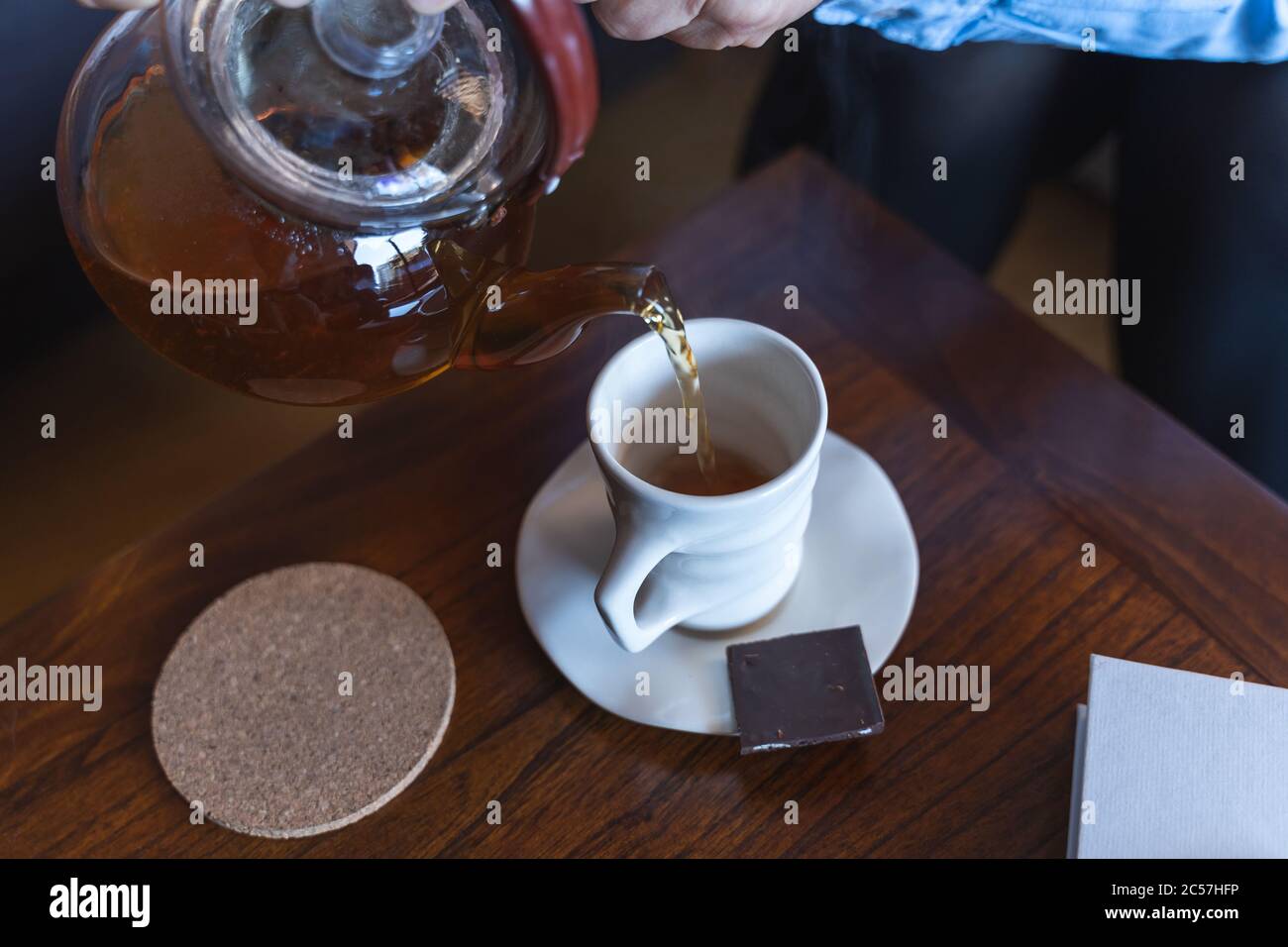 Person serving tea from a glass teapot in a ceramic cup with a piece of ...