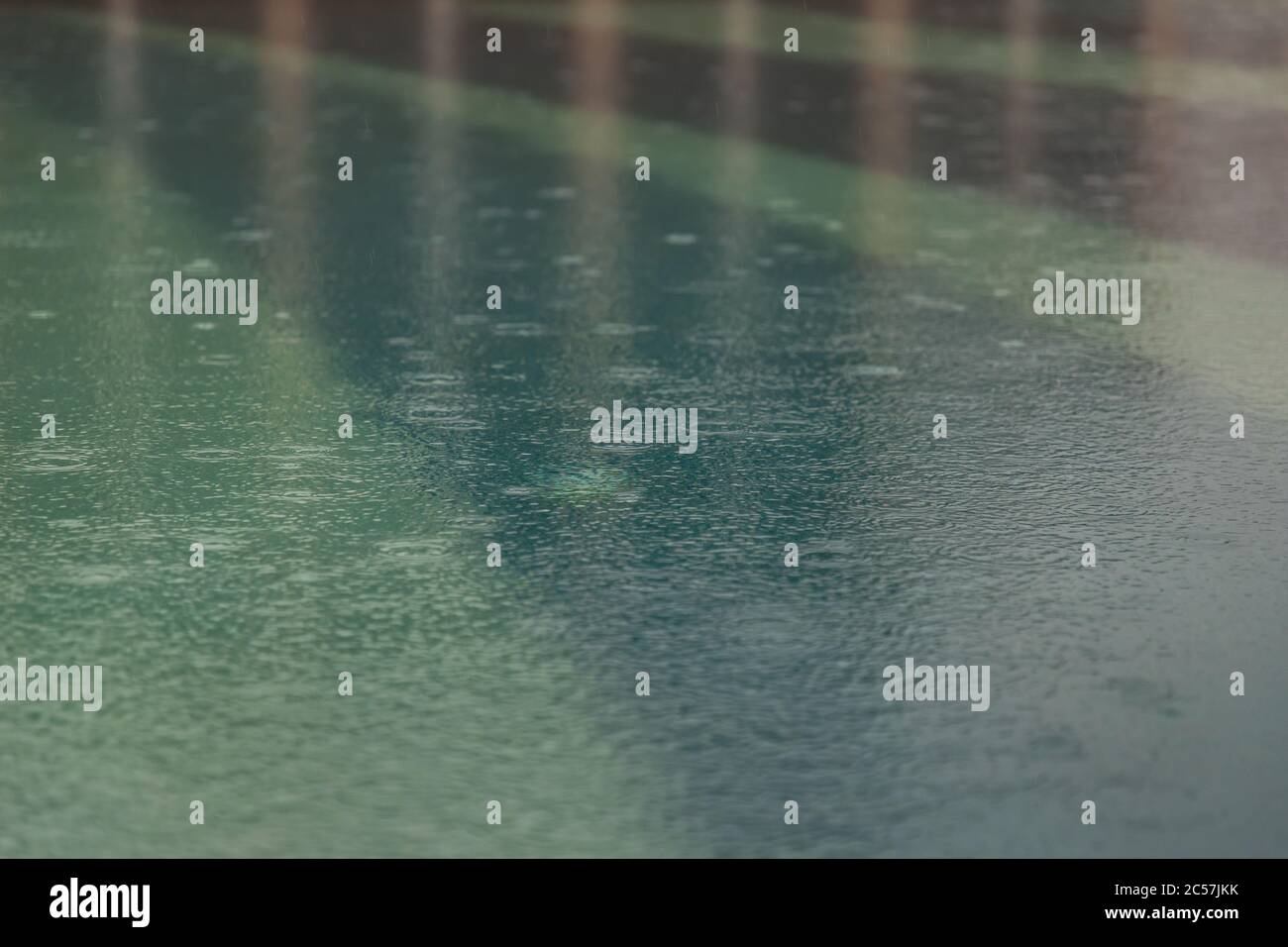 Rain drops falling in the swimming pool. Water surface for background ...
