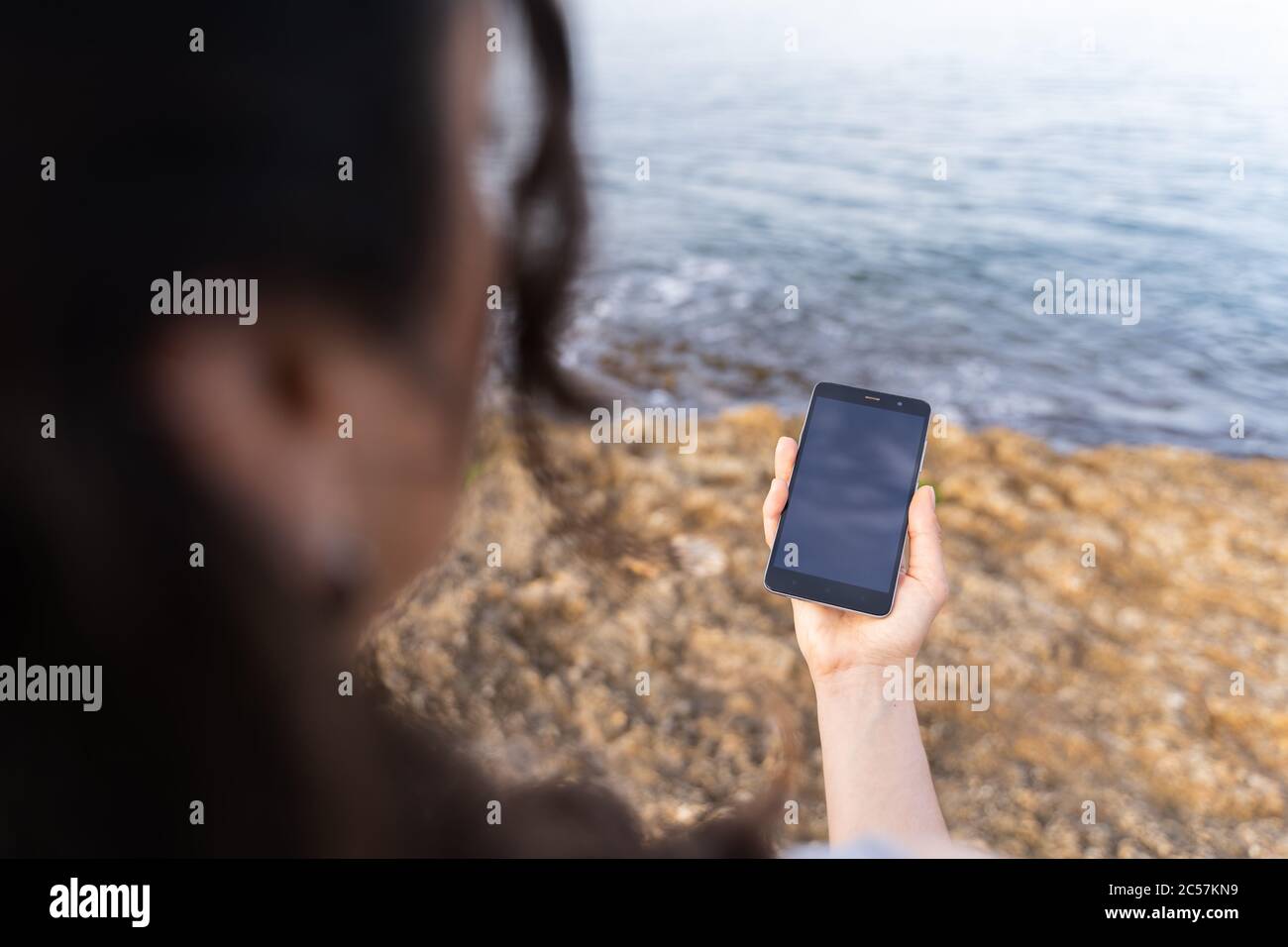 Girl holding her mobile phone in her hand while looking at it, head is ...