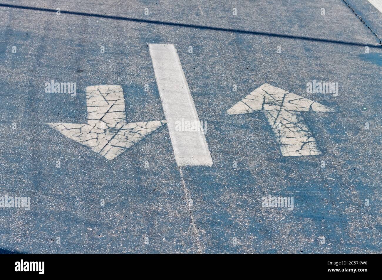 Horizontal signage of a blue cycle path with white directional arrows ...