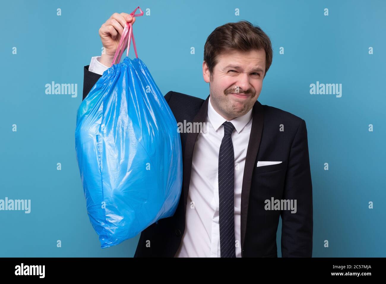 Man in suit holding blue garbage bag Stock Photo - Alamy