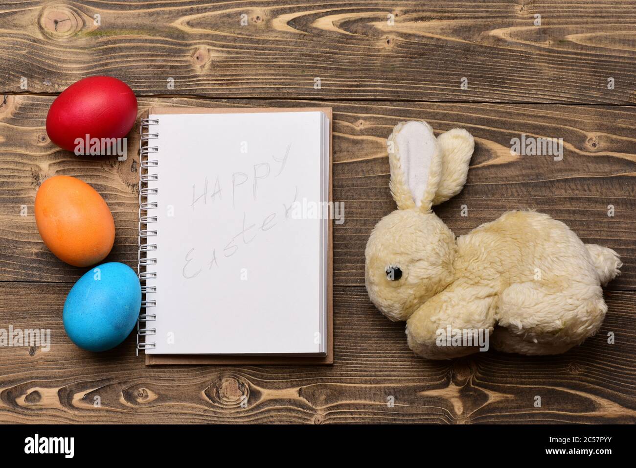 paper notebook, rabbit or hare toy, colorful painted eggs on wooden ...