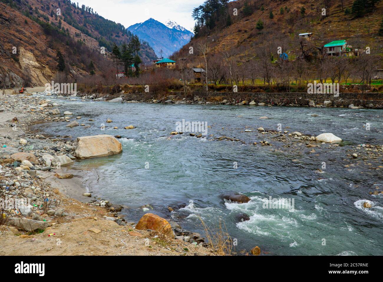 A river flowing on the side of road and mountain have rocks in the ...