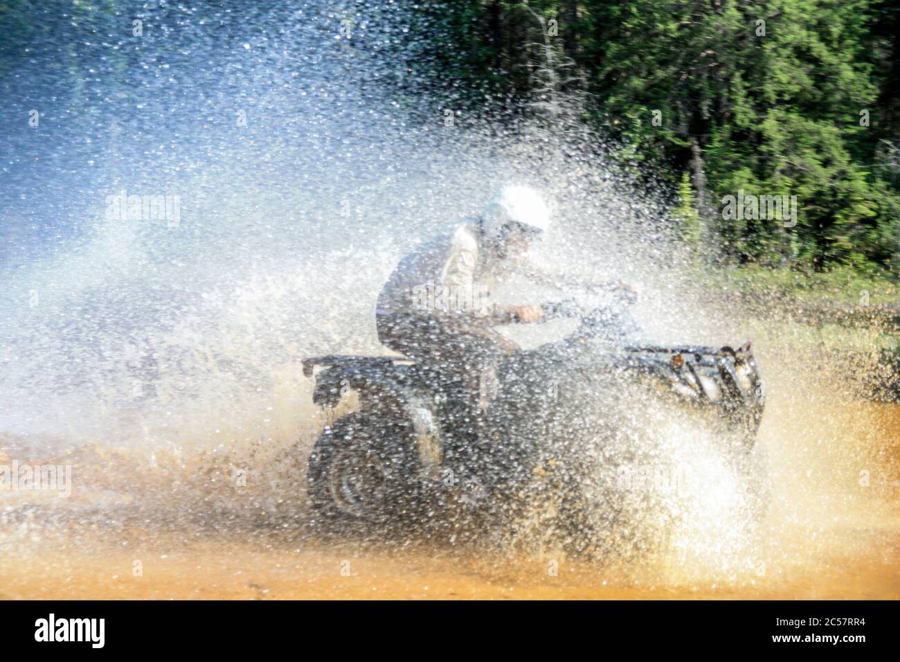 Man driving motocross ATV quad through splashing river lake water with ...